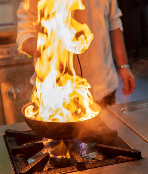 Chef Cooking With Fire In Frying Pan. Professional chef in a commercial ...