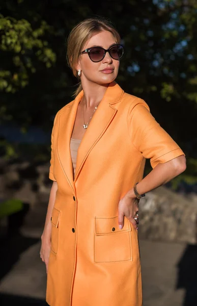 Woman in orange coat at street, woman outfit. Fancy style for ladies, autumn colors and fashion ...