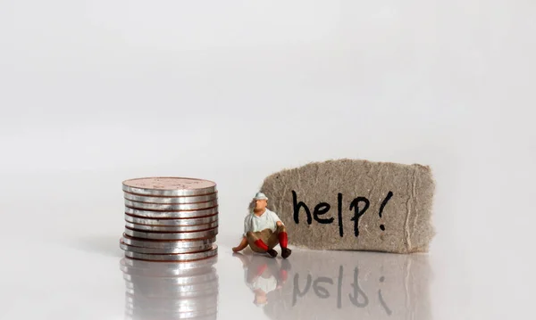 The 'help! word written on a torn cardboard. A stack of coins and a ...