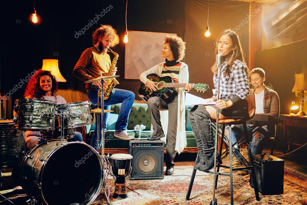 Práctica de la banda en casa estudio. Mujer cantando mientras el resto ...