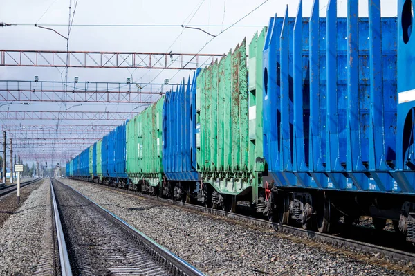 A freight train with blue and green wagons is parked at the railway ...