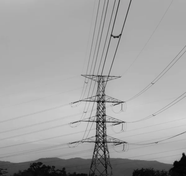 Shot of high voltage electric tower with power lines over tropical rain ...