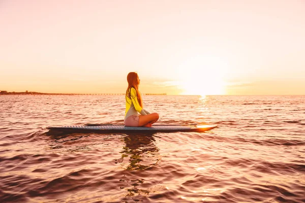 Stand up paddle boarding on a quiet sea with sunset colors. Relax in ...