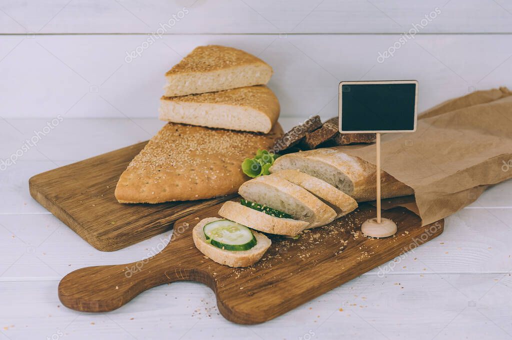 Varios tipos de pan con lechuga y pepinos en las tablas de la cocina en ...