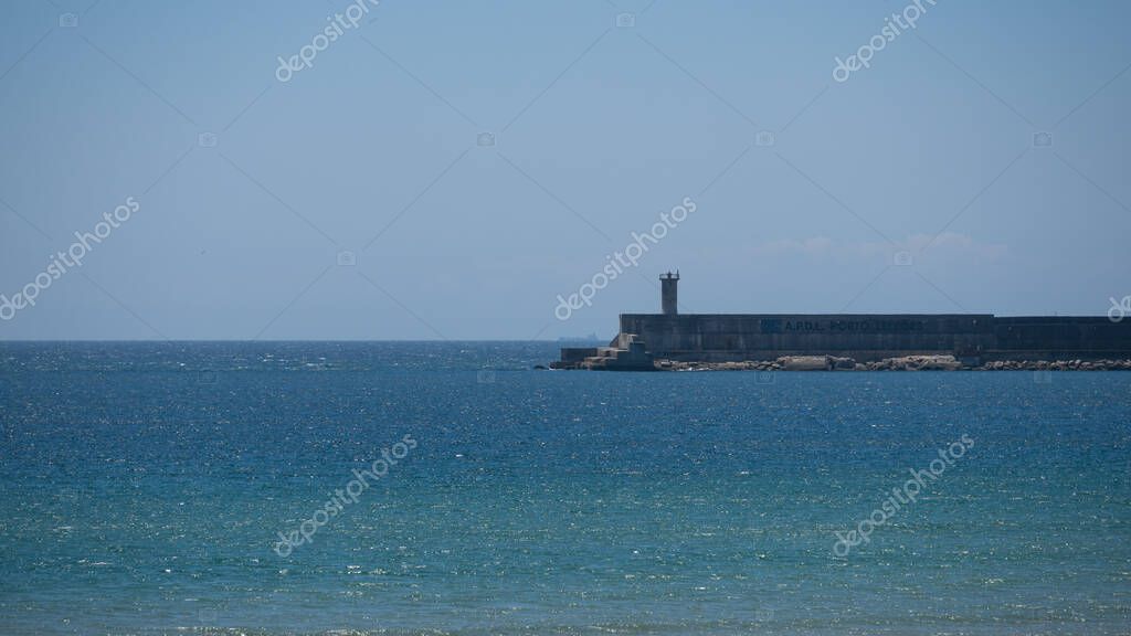 Muro de mar con faro, sobresaliendo hacia el océano en el horizonte ...