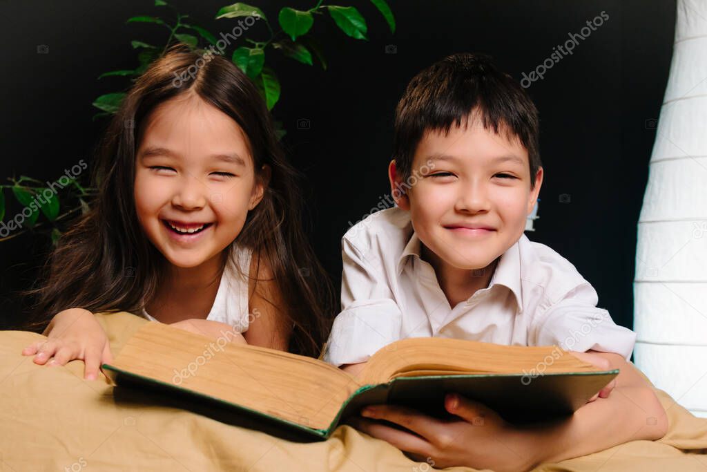 Retrato de dos hermanos asiáticos riéndose leyendo un libro juntos en ...