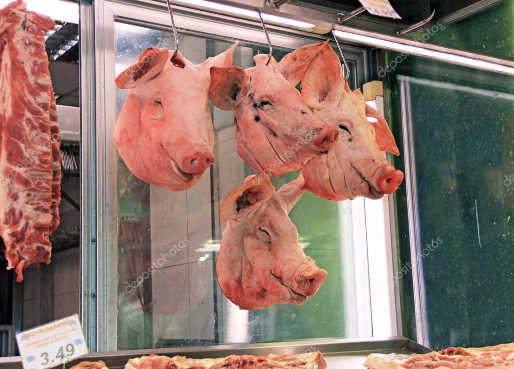 Cabezas de cerdo cortadas colgando en el enorme mercado público central ...