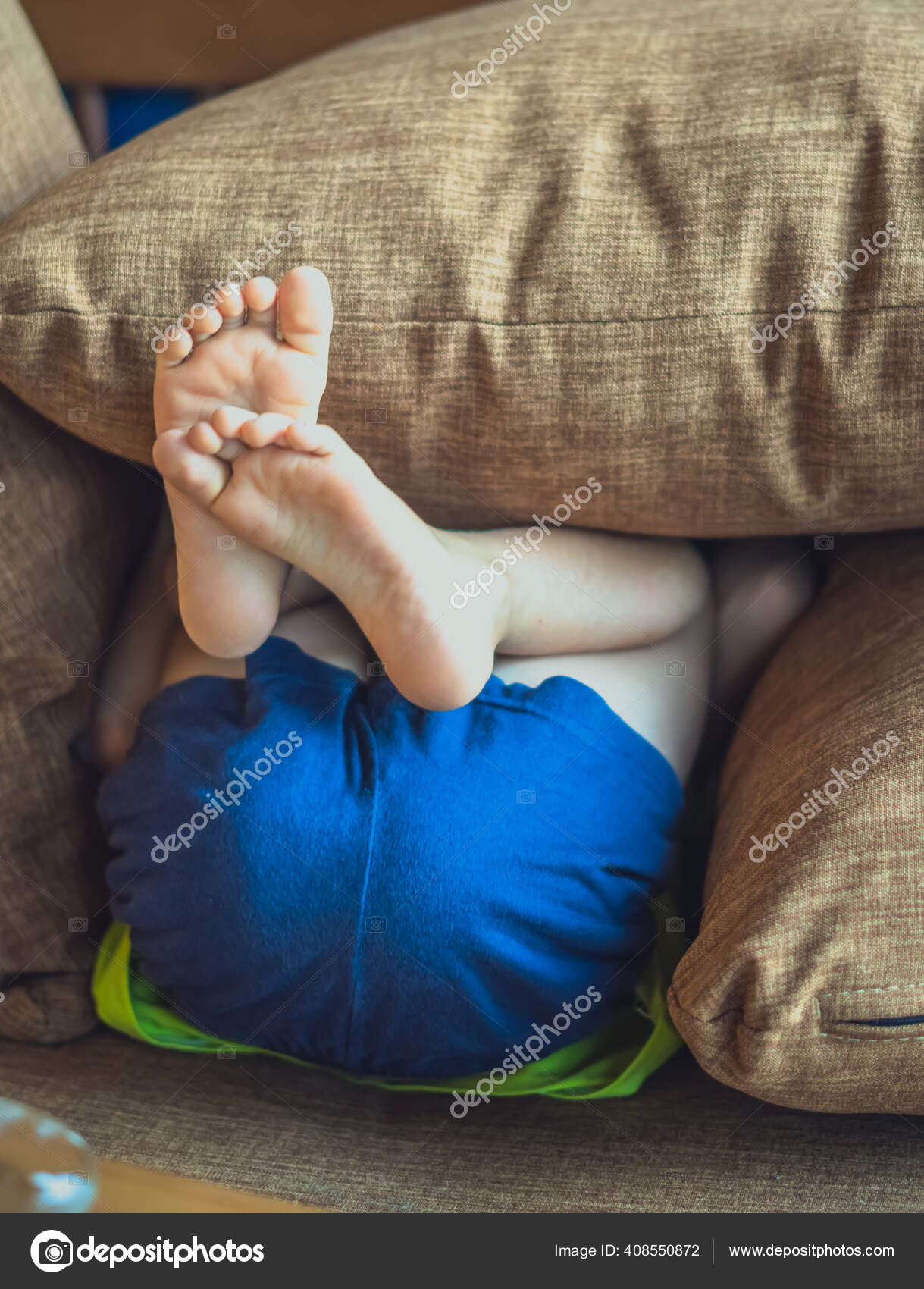Rear view, back butt legs feet of a child hiding under a pillow ...