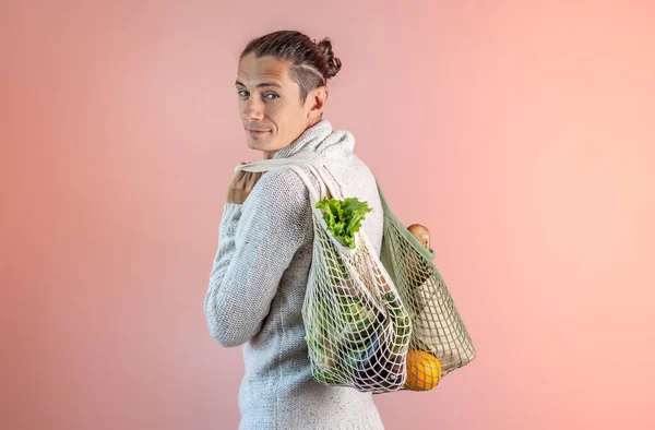 A modern young man is carrying a string bags with purchases. Concept of ...