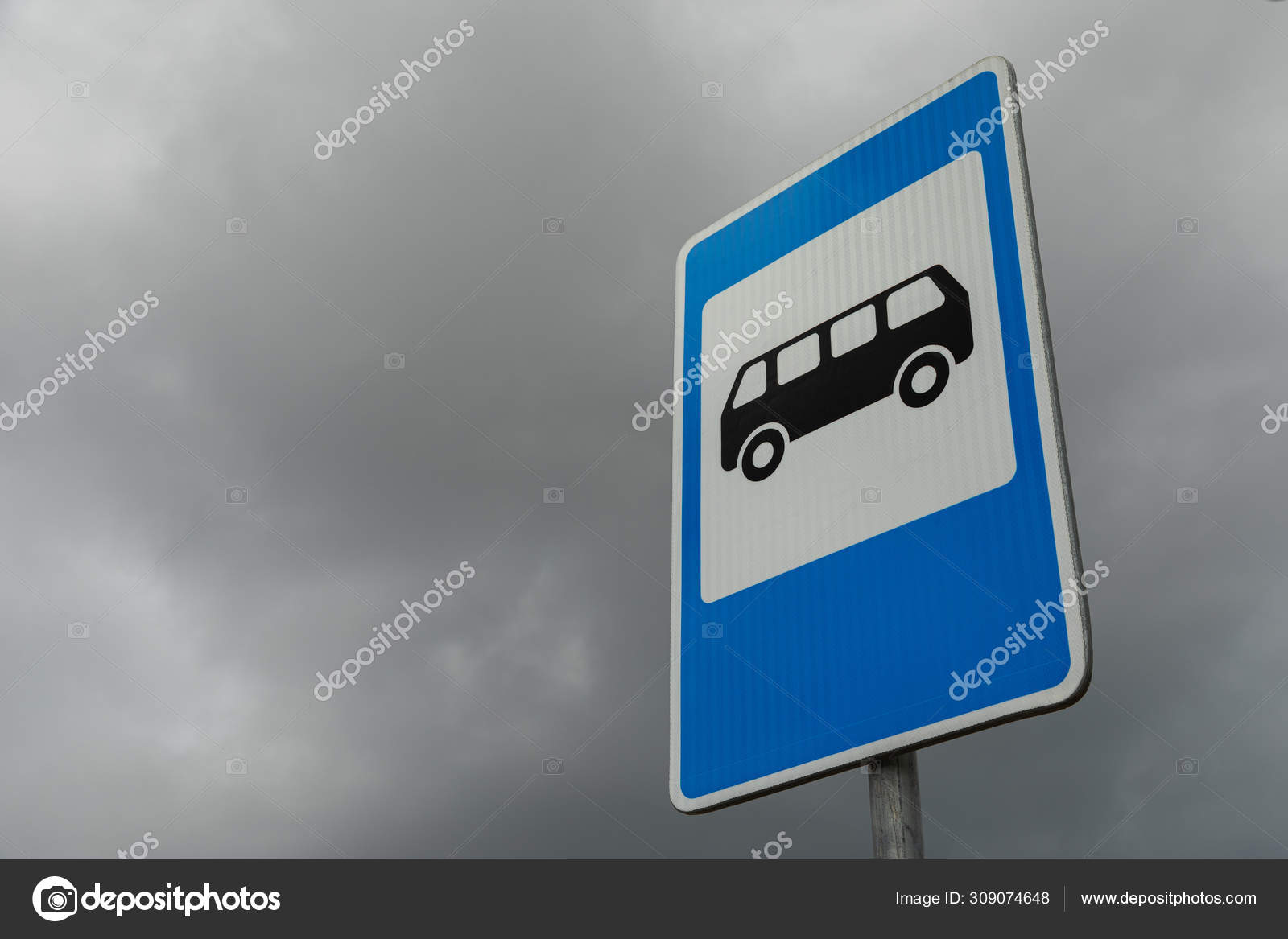 Right angled blue and white roadsign of bus stop against gloomy cloudy ...