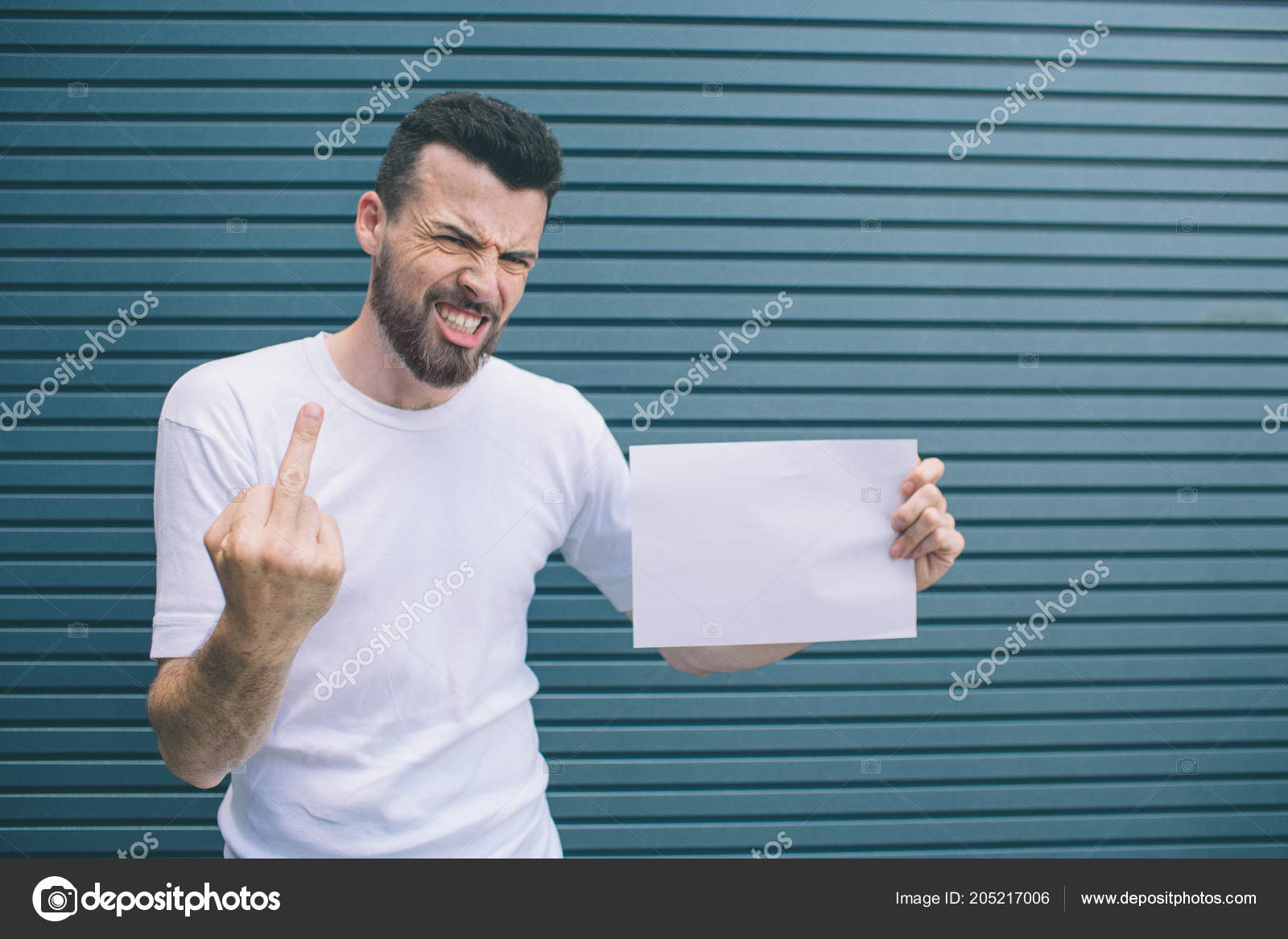 Angry man is standing and posing on camera. He is showing third finger ...