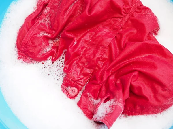Washing color red pants with hand and soak cloth in laundry detergent ...