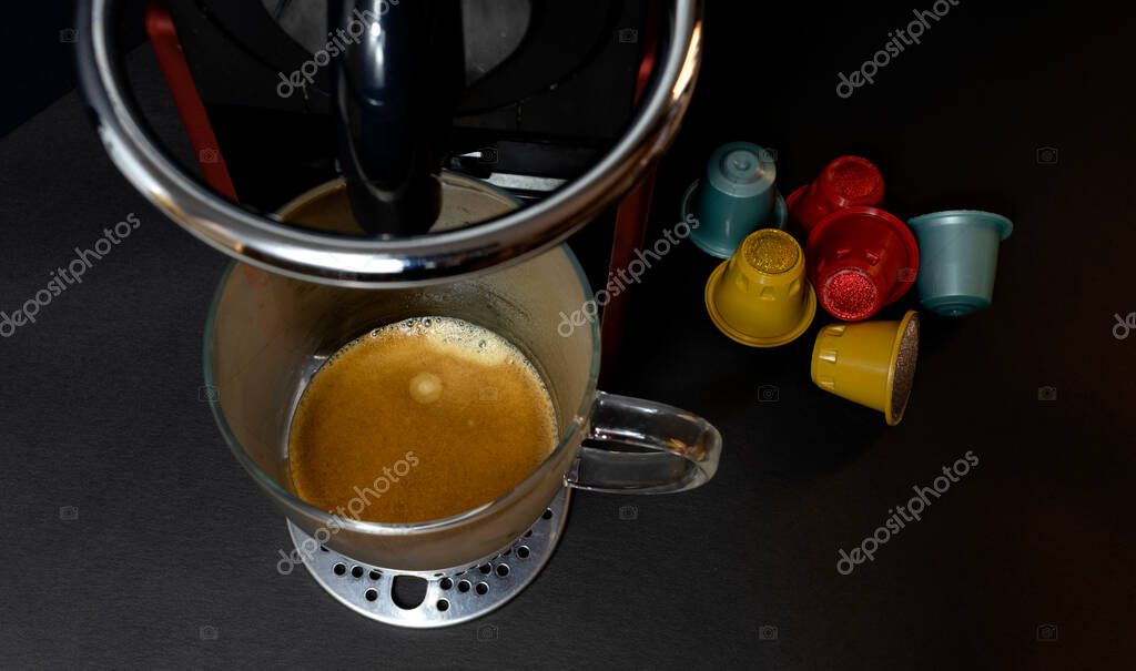 Un delicioso caf con espuma hecha por una cafetera c psula y varias c psulas de colores junto a ...