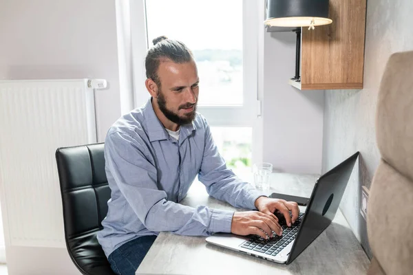 The guy sits at the computer and looks at the laptop monitor and ...