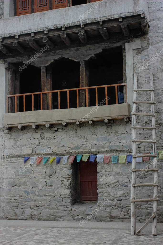 Escalera de madera, balcón y banderas budistas, frente a una casa ...