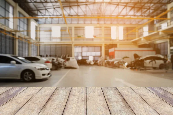 Wood table top with Car repair service centre interior blurred ...