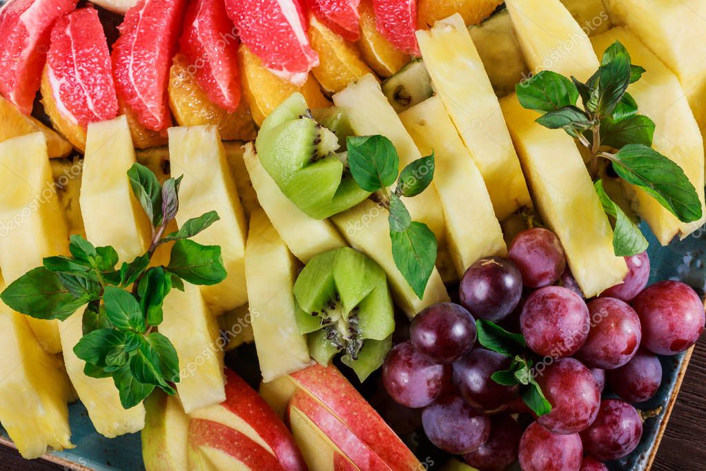 Surtido de frutas frescas en el plato. Manzana, uvas, kiwi, piña ...