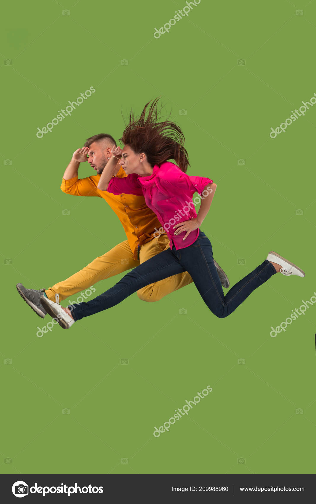 Freedom in moving. Pretty young couple jumping against green background ...
