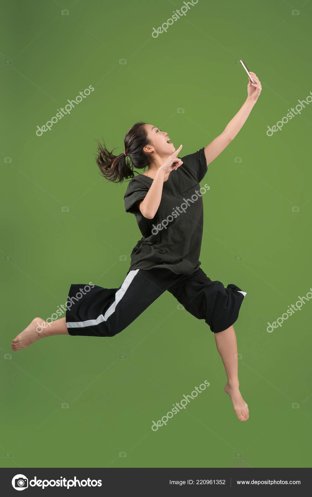 Freedom in moving. Pretty young woman jumping against green background ...