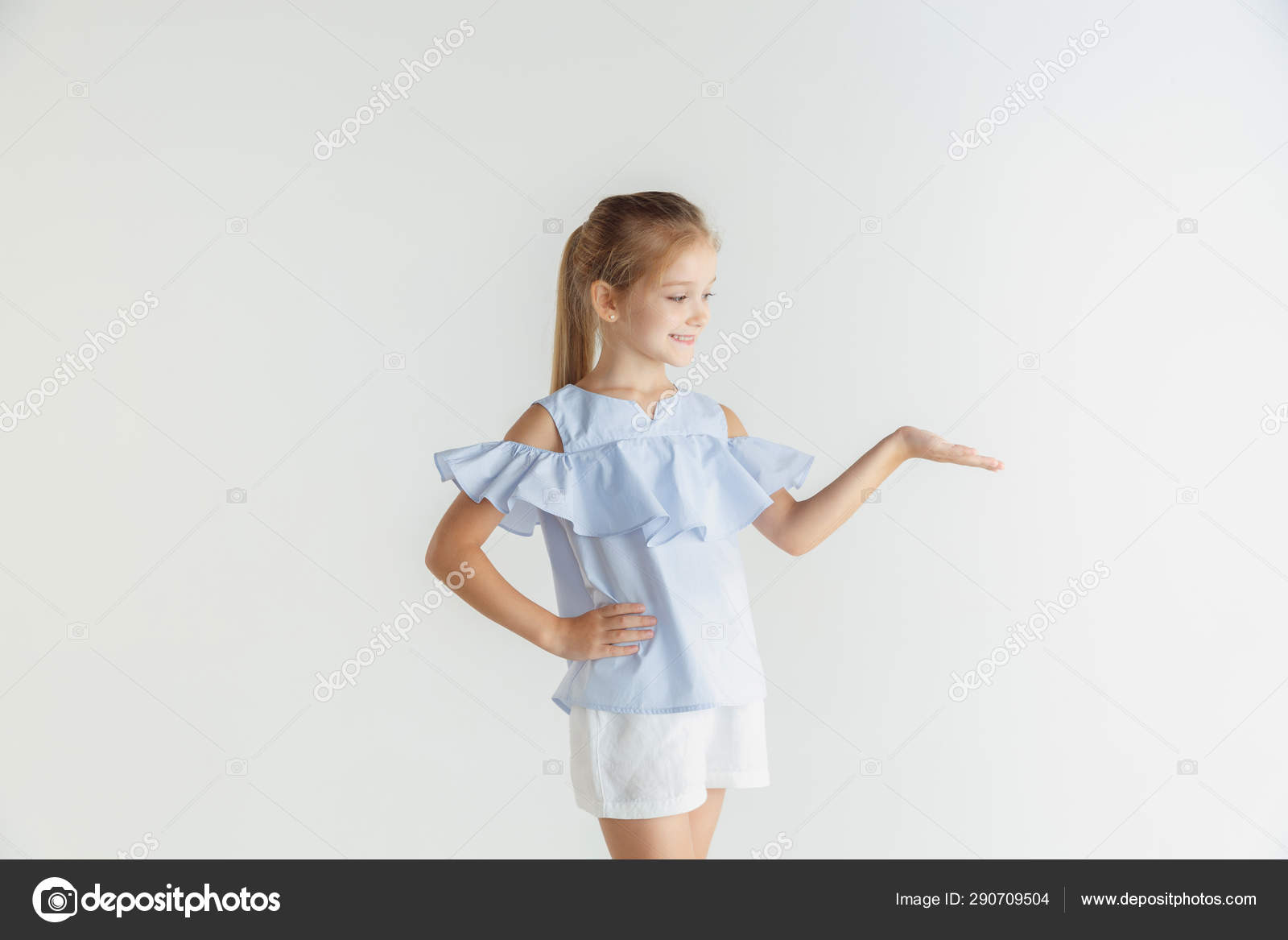 Little smiling girl posing in casual clothes on white studio background ...