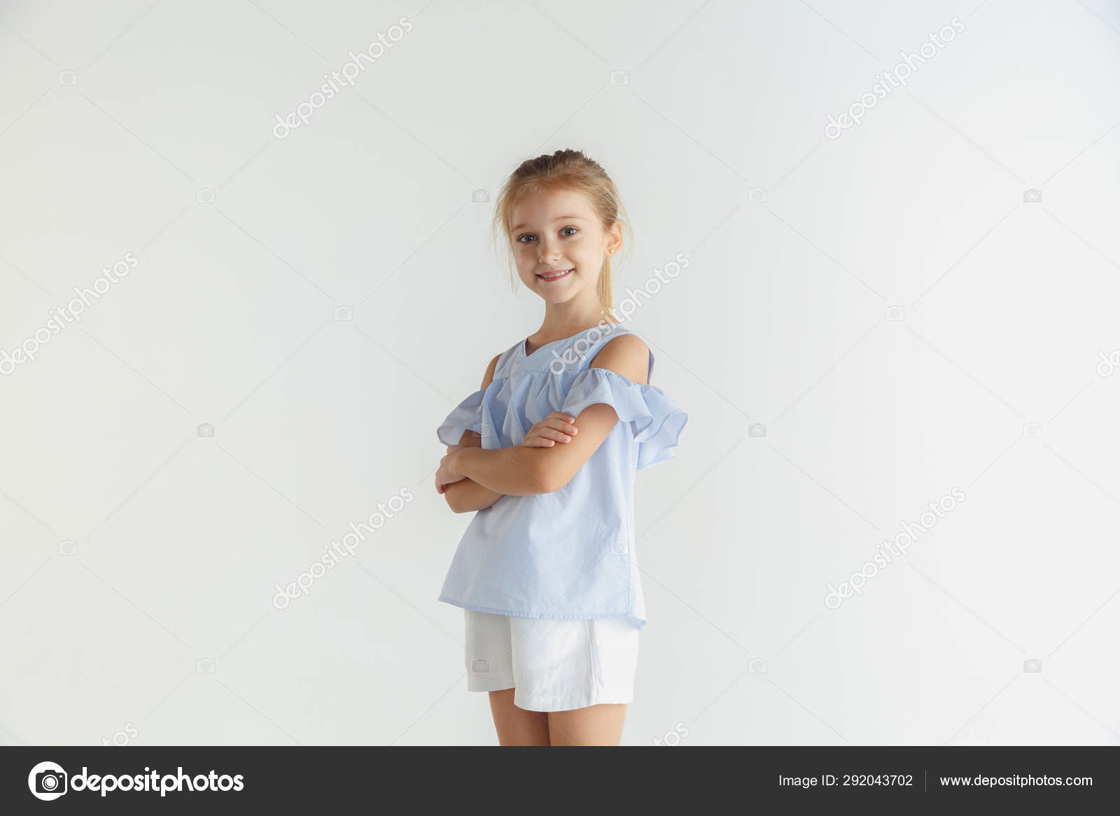 Little smiling girl posing in casual clothes on white studio background ...
