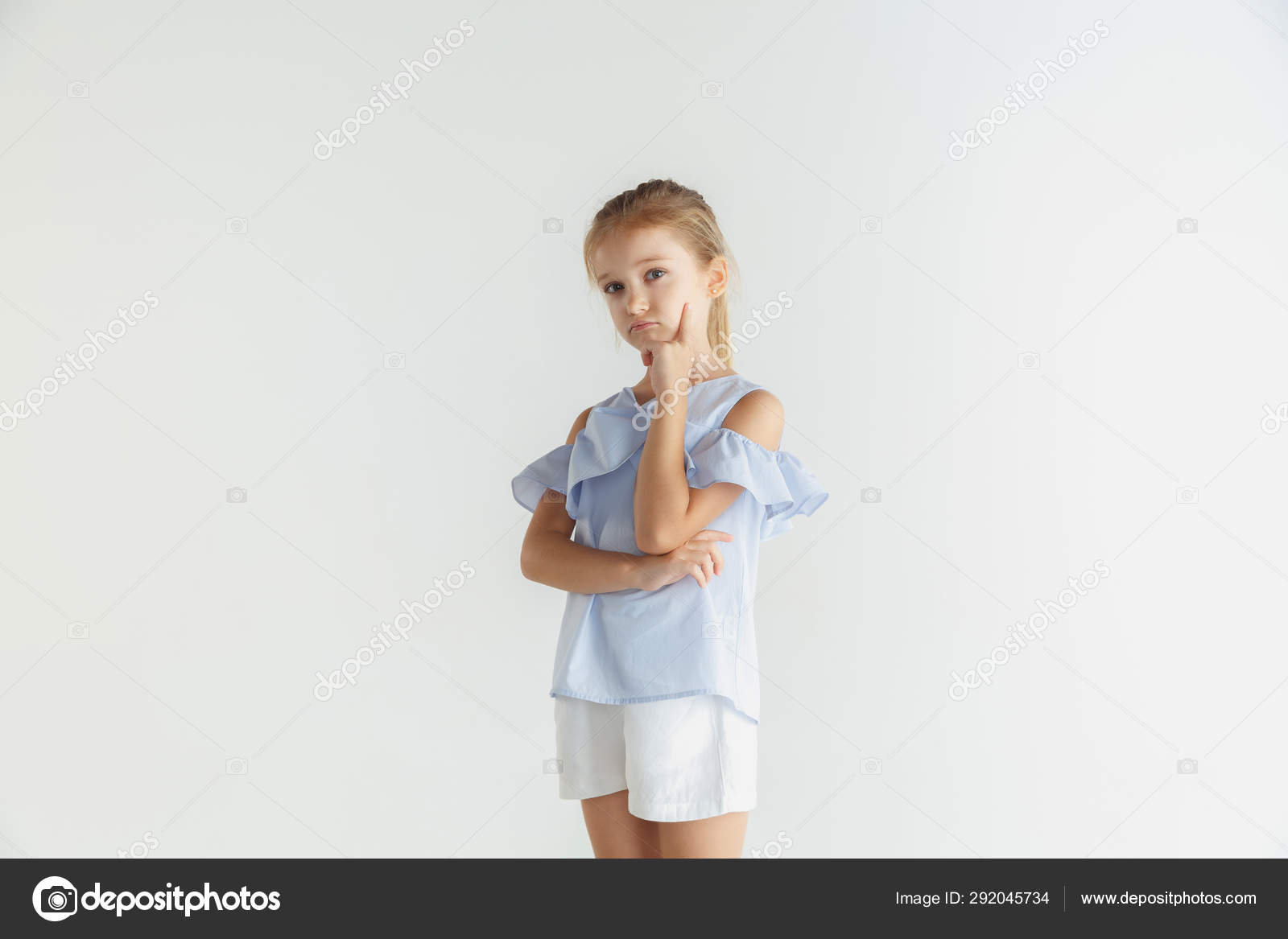 Little smiling girl posing in casual clothes on white studio background ...