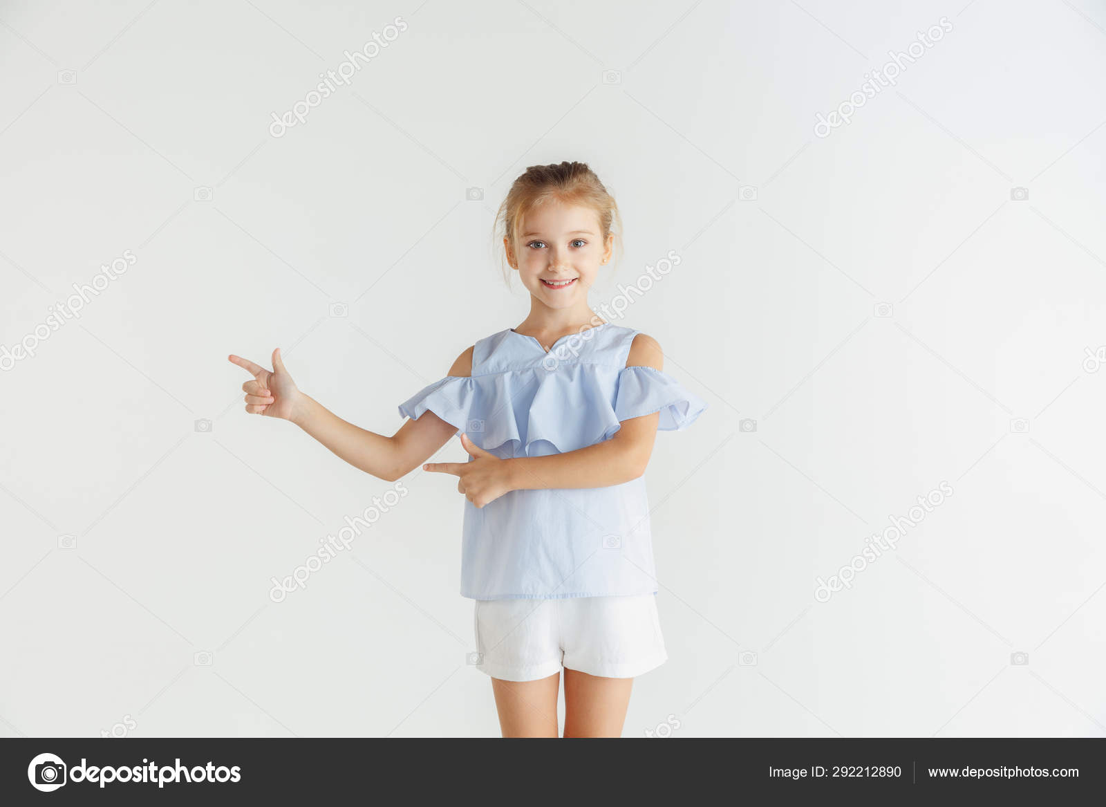 Little smiling girl posing in casual clothes on white studio background ...