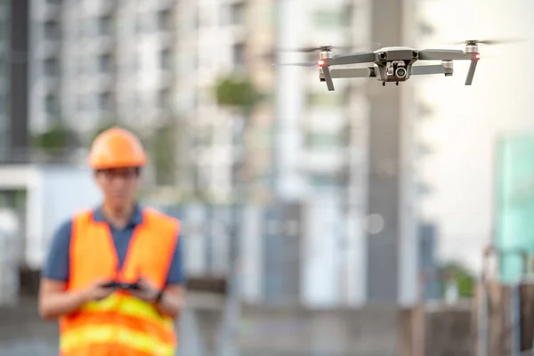 Young Asian engineer flying drone over construction site. Using ...