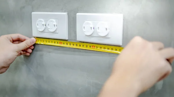 Male hand electrician using tape measure for measuring dimension of ...