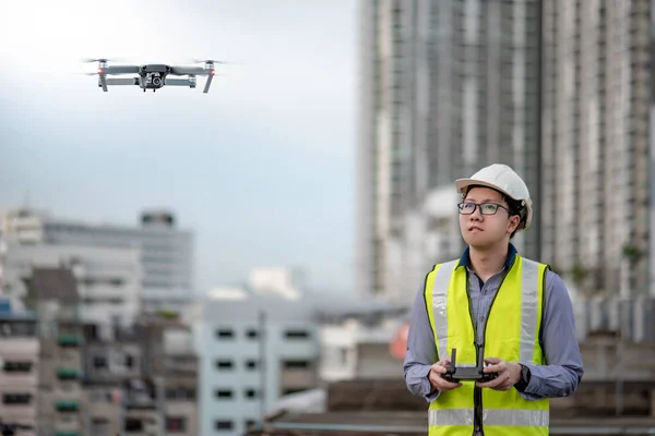 Asian engineer man flying drone over construction site. Male worker ...