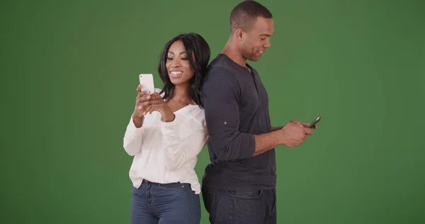 Couple standing back to back texting on cell phones on green screen ...