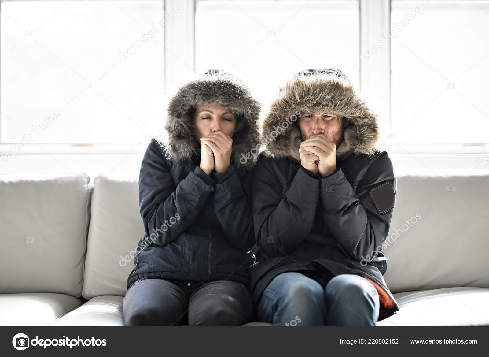 Couple have cold on the sofa at home with winter coat Stock Photo by ...