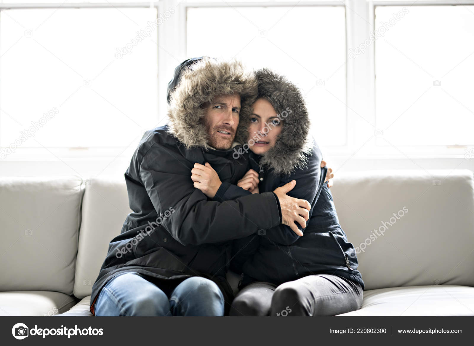 Couple have cold on the sofa at home with winter coat Stock Photo by ...