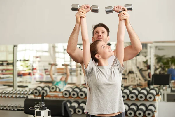 Personal trainer helping a young woman lift weights. - Stock Image ...