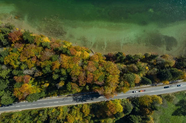 Top view drone shot of a lake with a colorful forest at autumn and a ...