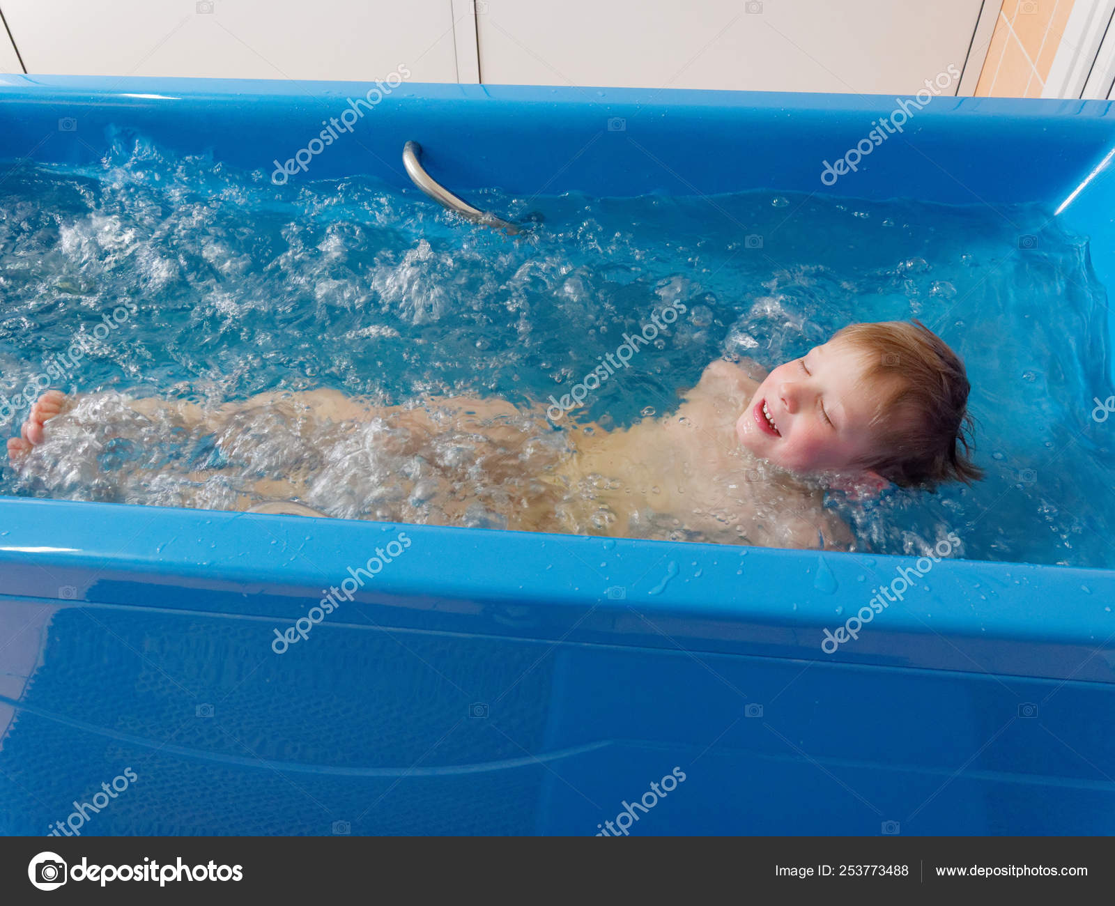Baby boy is taking a bath with bubbles. Jacuzzi bubble bath procedure ...