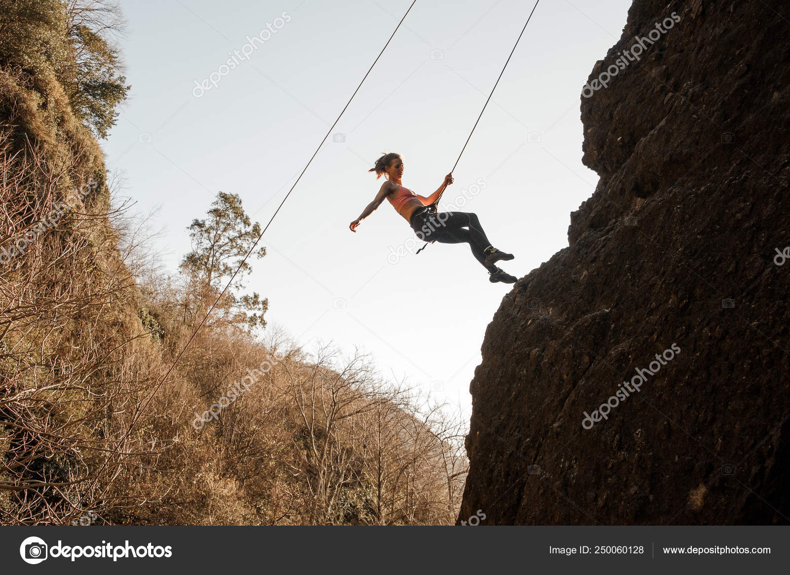 Girl equipped with a rope abseiling on the sloping rock Stock Photo by ...