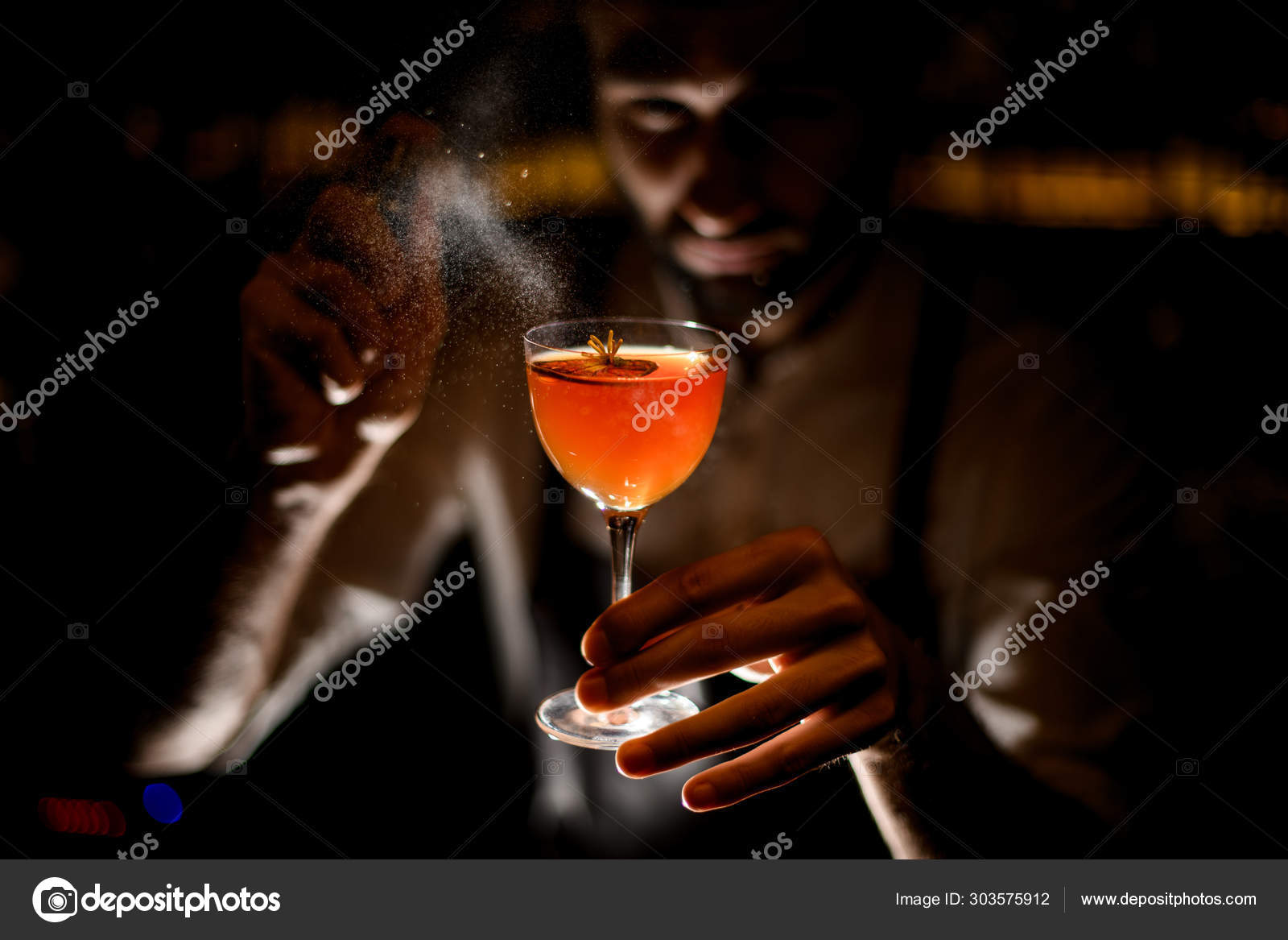 Professional male bartender serving a brown orange cocktail spraying on ...