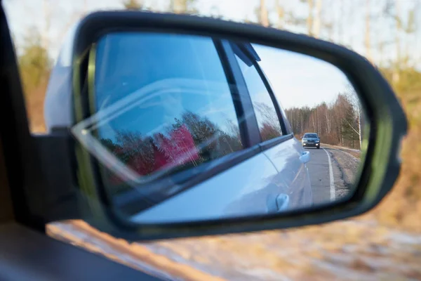 Side mirror of the car and the reflection of the road in it. Autumn ...