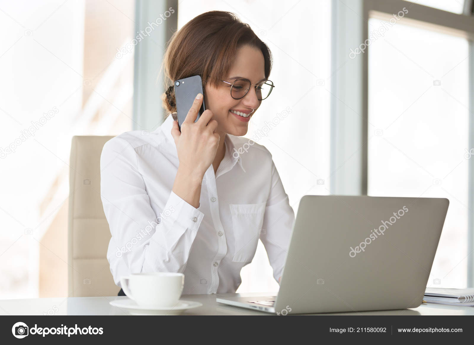 Smiling confident businesswoman making phone call using laptop i ... Smiling confident businesswoman making phone call using laptop i ...