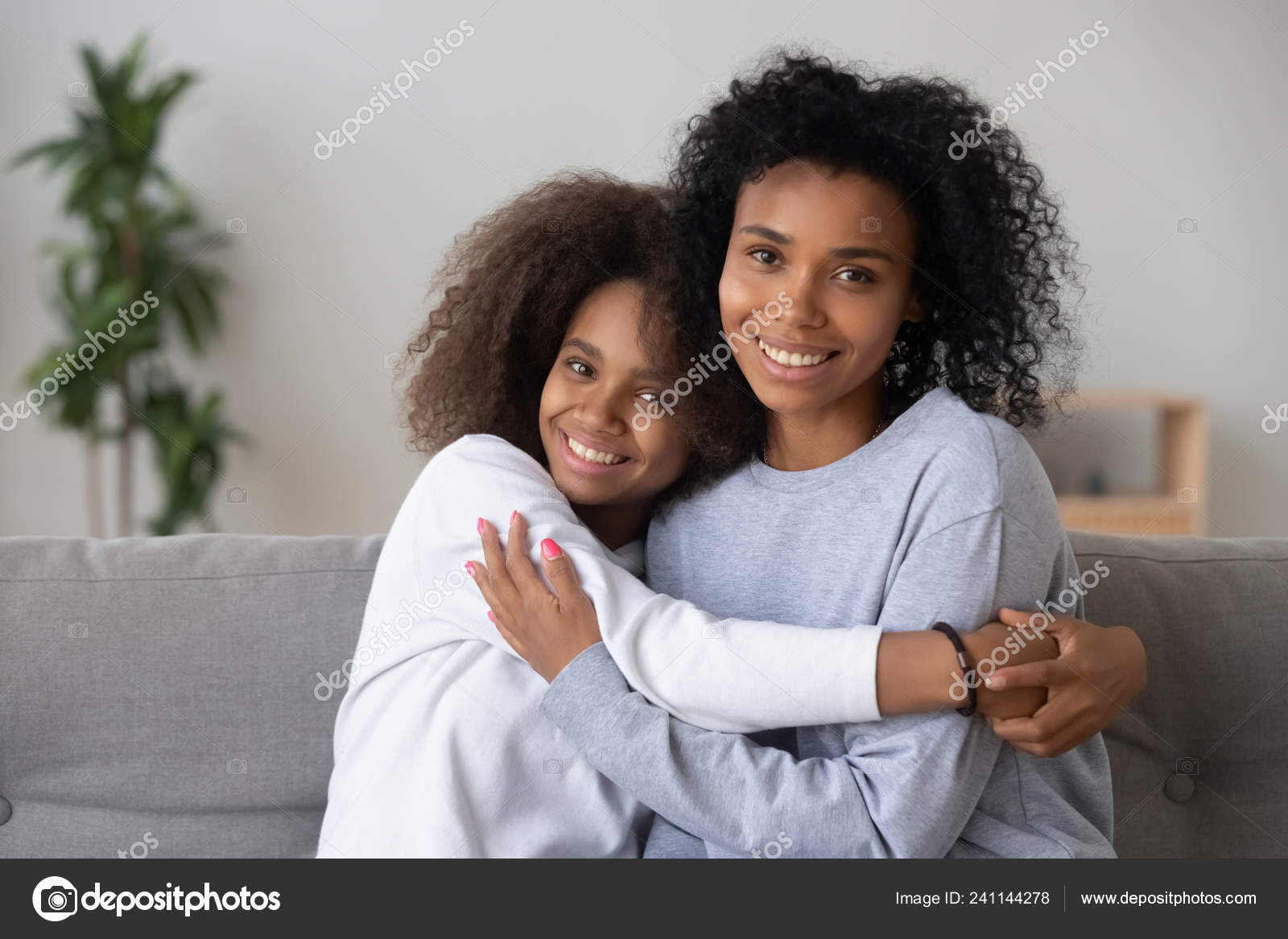 Portrait of smiling black mom and daughter hugging on couch — Stock Photo © fizkes #241144278