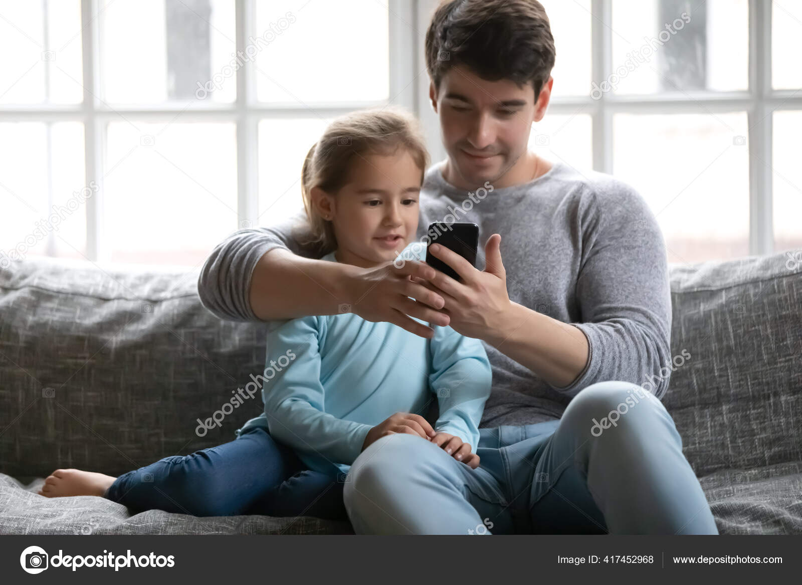 Caring dad and small daughter use smartphone together — Stock Photo © fizkes #417452968