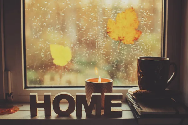 cozy autumn morning at home. Hot tea and candle on window in rainy cold ...
