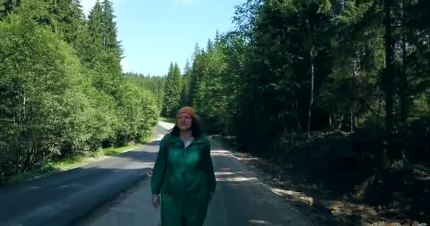 Women walking alone on an empty road, in the middle on the forest ...