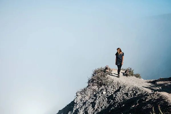 Young woman in protective mask on summit of active volcano Kawah Ijen ...