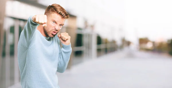 young blonde man with an angry, aggressive and menacing pose, ready for ...