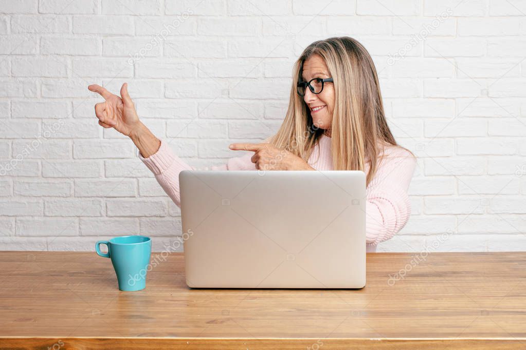 mujer de negocios mayor sonriendo y se alando a un lado con ambas manos, hacia el lugar donde el ...