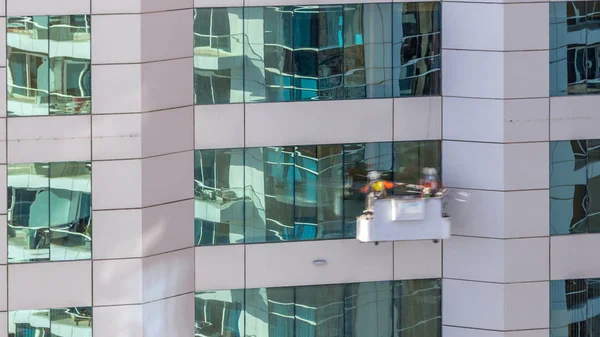 Washers wash the windows of modern skyscraper timelapse. Aerial view ...