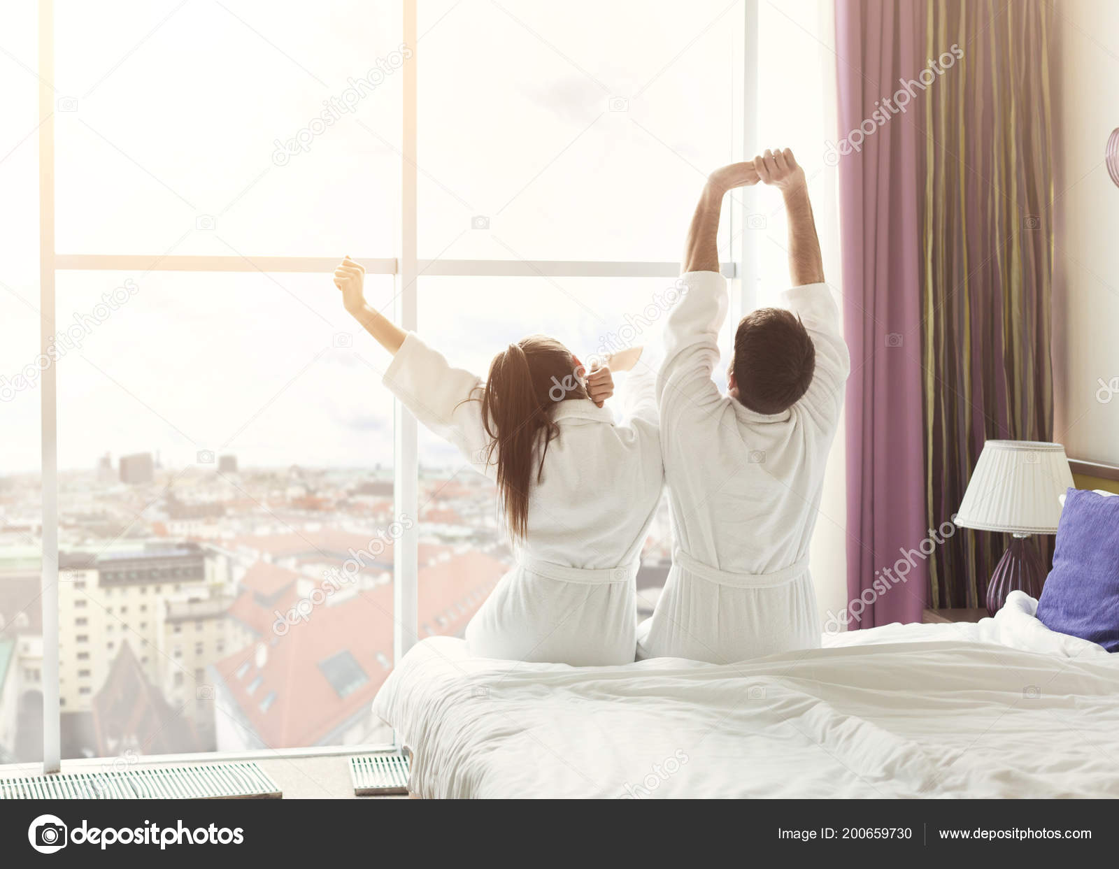 Young couple waking up in the morning in hotel room Stock Photo by ...