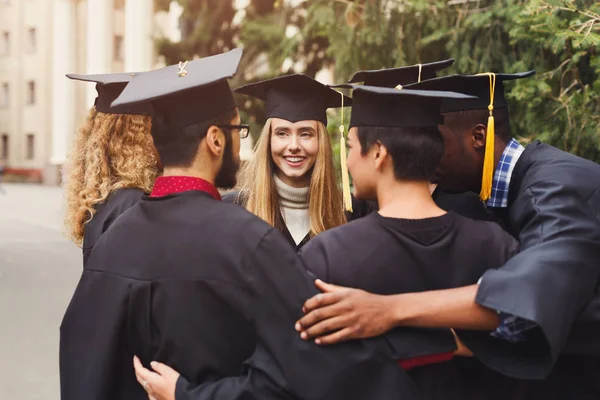 Graduates having group hug on graduation day - Stock Image - Everypixel